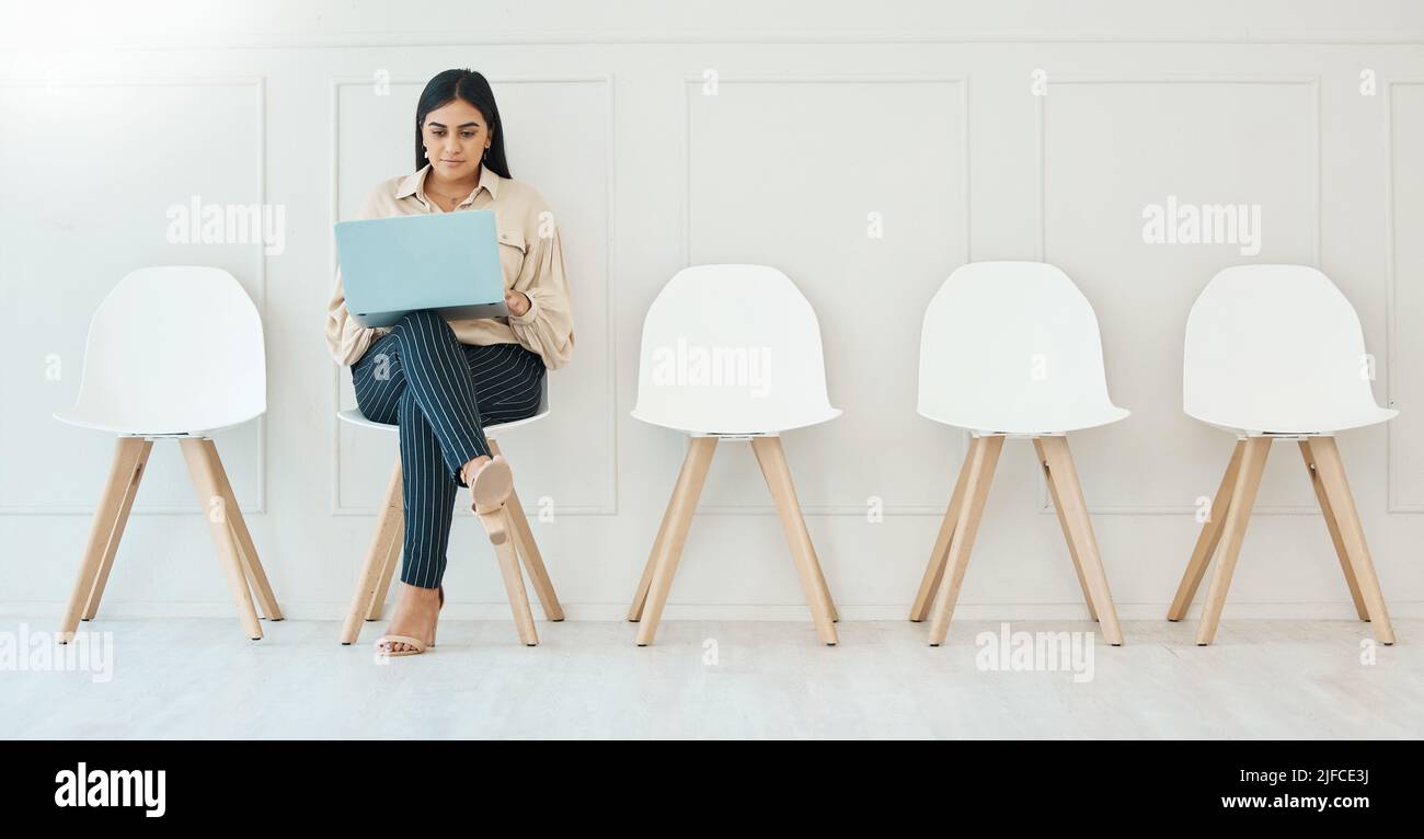 Full body indian businesswoman sitting alone and using a laptop to ...