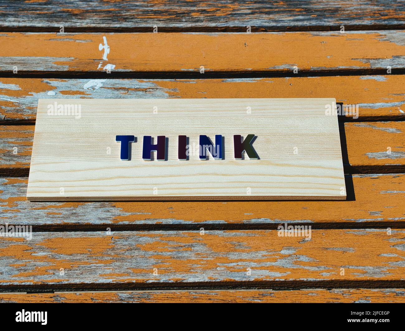 The word Think in rainbow colored lettering on an old rustic orange ...