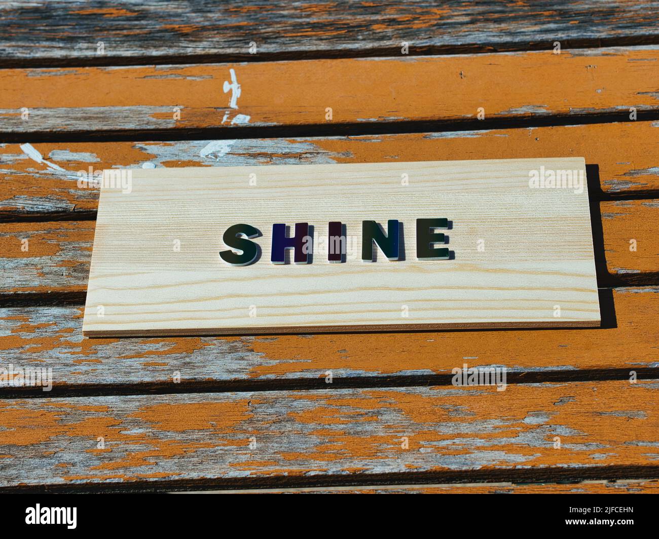 The word Shine in rainbow colored lettering on an old rustic orange ...