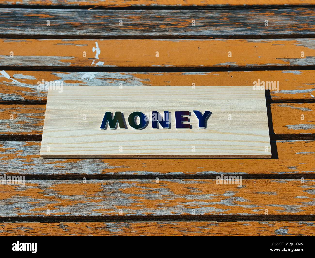 The word Money in rainbow colored lettering on an old rustic orange ...