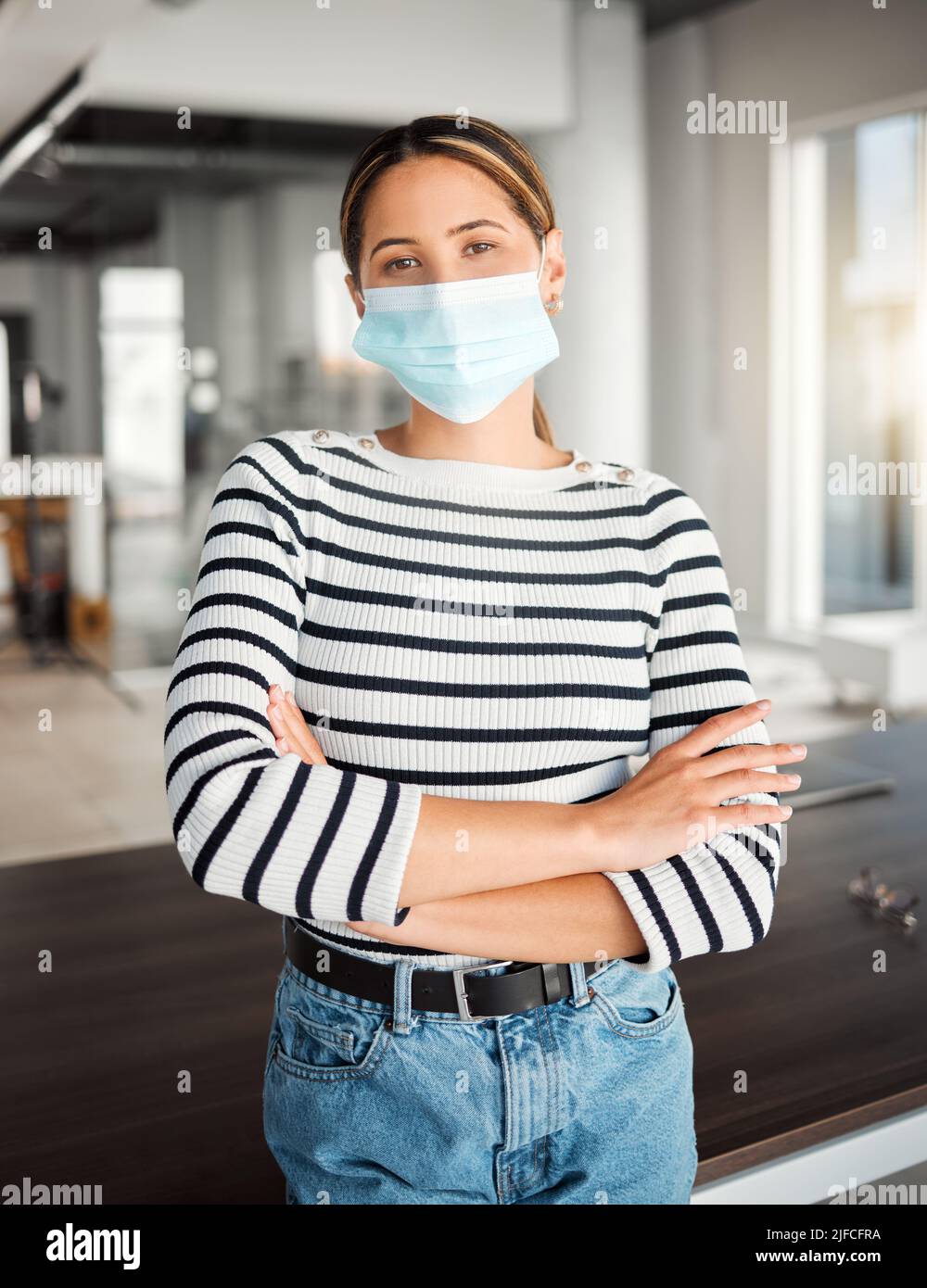 Young mixed race businesswoman standing with her arms crossed and ...