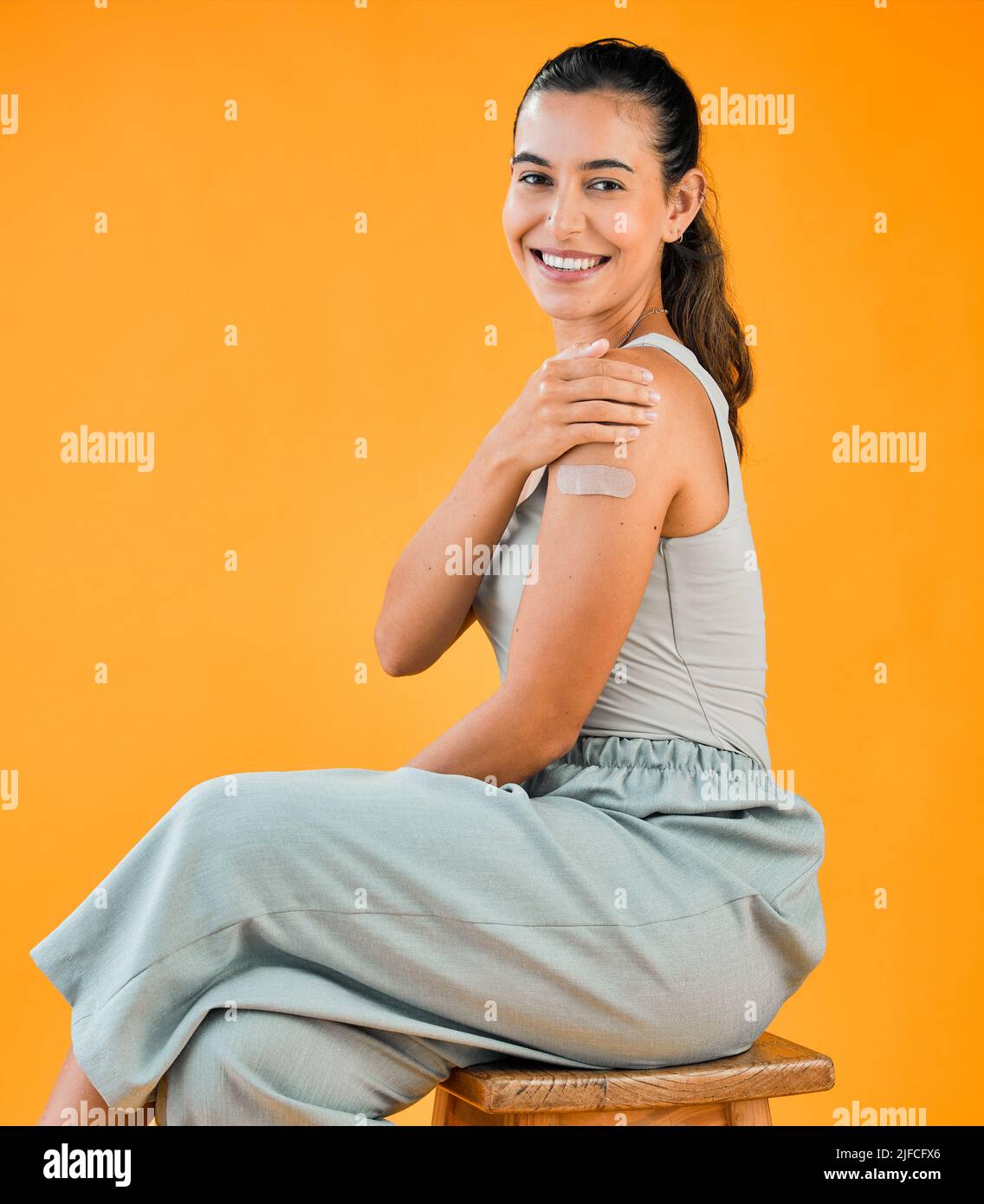 Mixed race covid vaccinated woman showing plaster on arm and smiling ...
