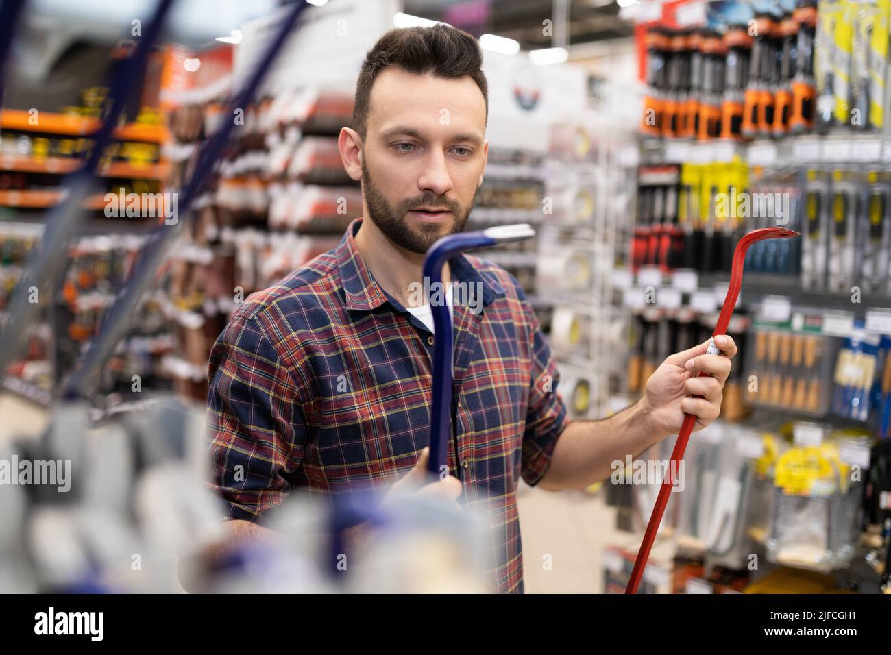 a young man in a hardware store chooses a nail puller Stock Photo - Alamy