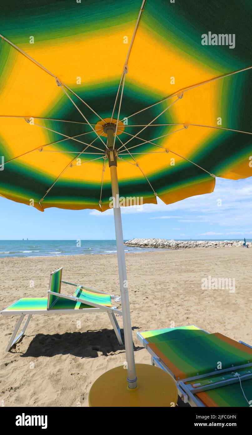 sandy beach by the sea under an umbrella with deck chairs without ...