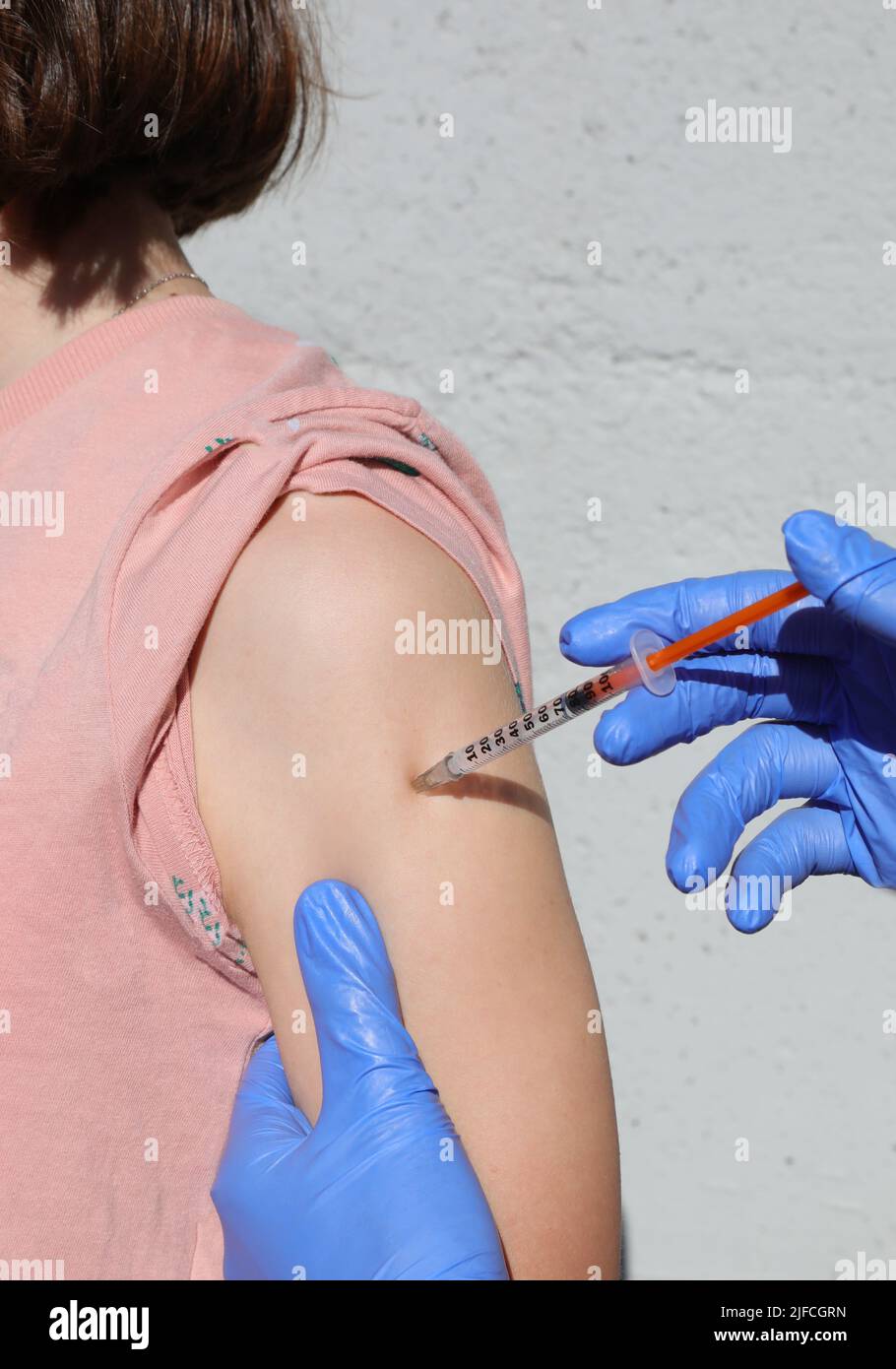 vaccinating young schoolgirl with syringe with mRna vaccine and arm ...