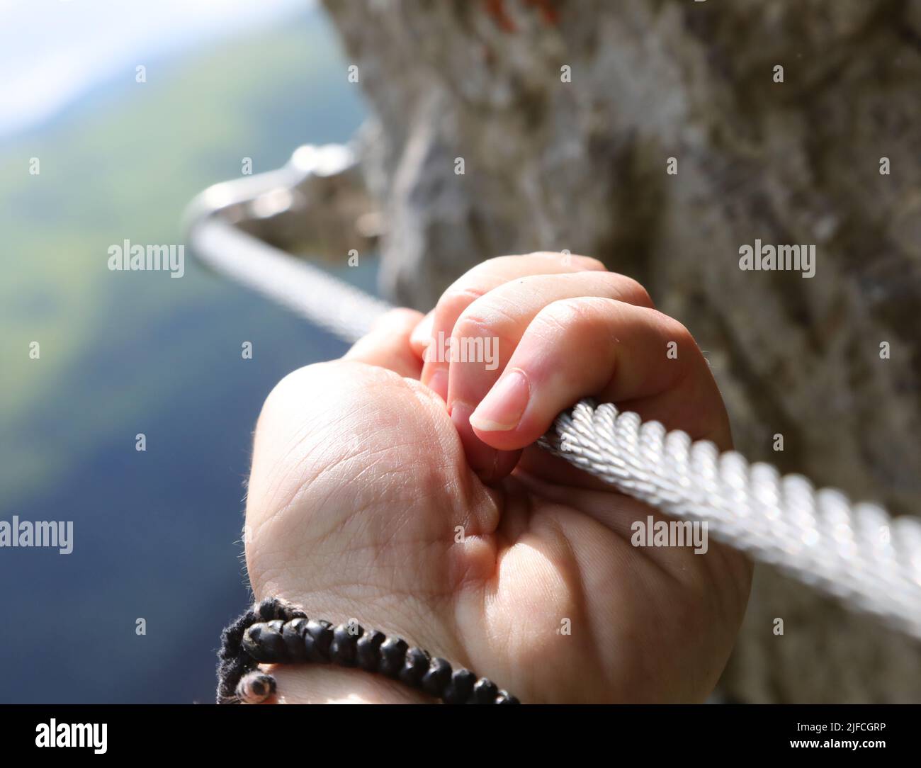 climber's hand while holding to the steel rope on a high mountain rock ...