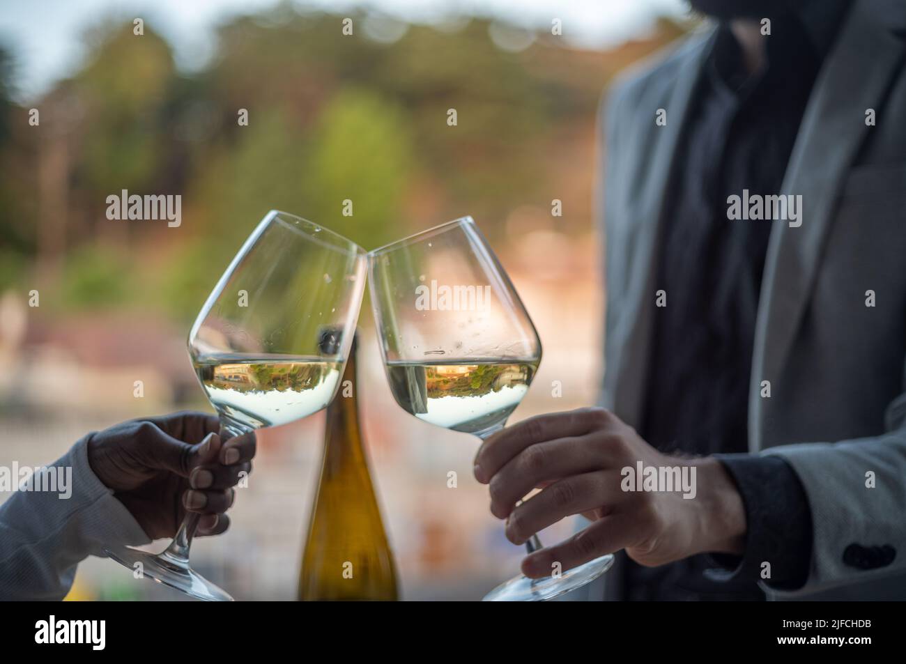 Interracial couple cheering with white wine on rooftop bar Stock Photo ...