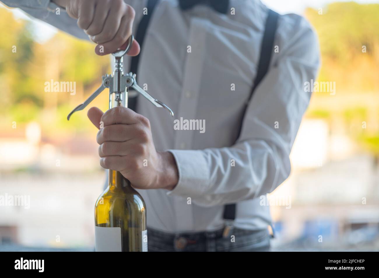 Fancy waiter using a cork screw on a rooftop bar Stock Photo - Alamy
