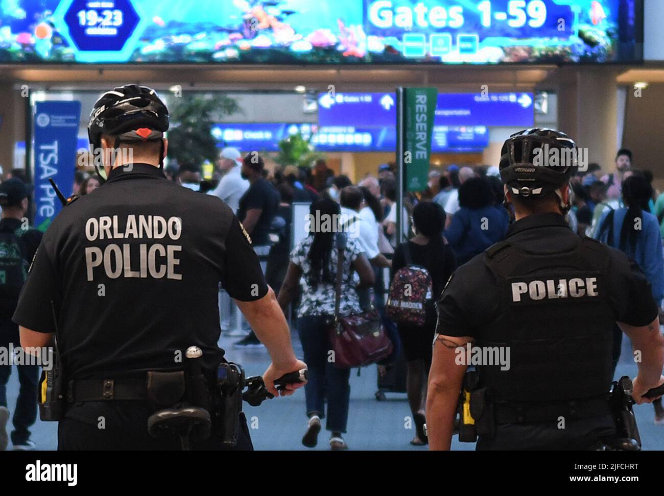 Orlando, USA. 01st July, 2022. Police officers watch as travelers make their way through a TSA ...