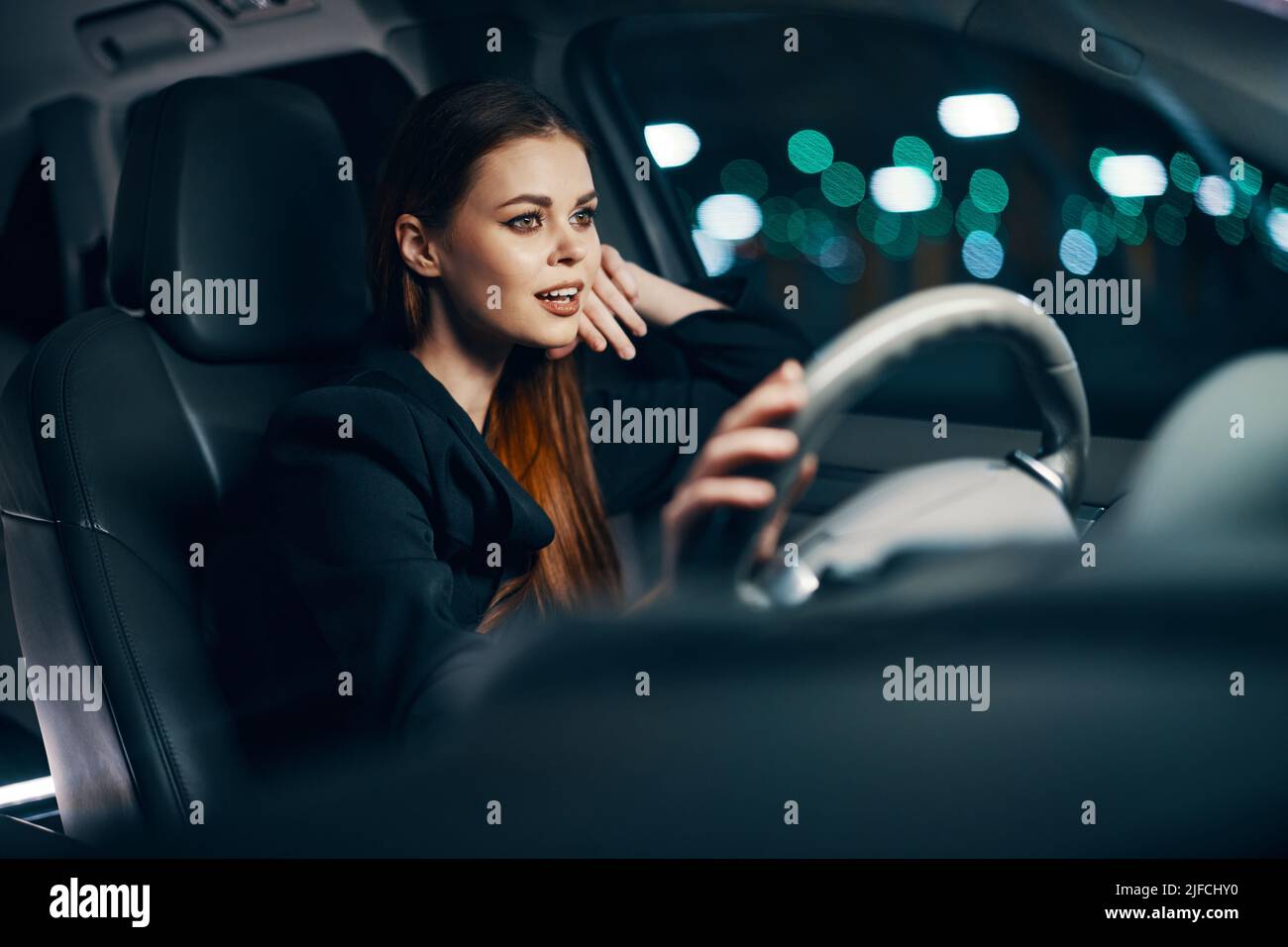 horizontal photo of a cute, relaxed woman sitting behind the wheel of a ...