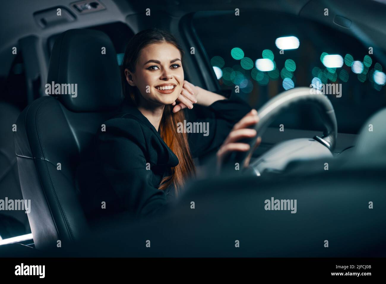 horizontal photo of a cute, relaxed woman sitting behind the wheel of a ...