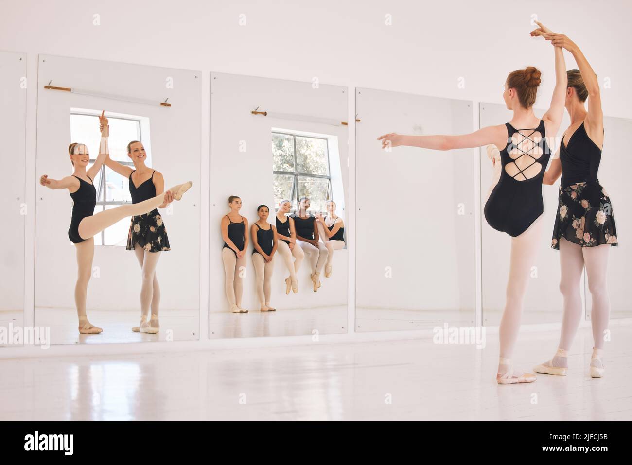 Young woman dance instructor teaching a ballet class to a group of a ...