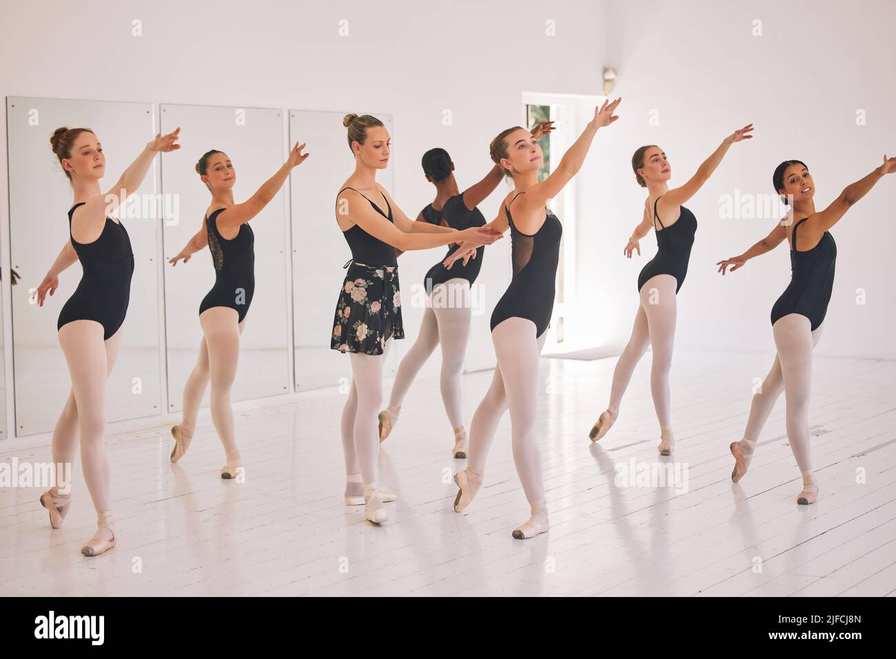 Young woman dance instructor teaching a ballet class to a group of a ...
