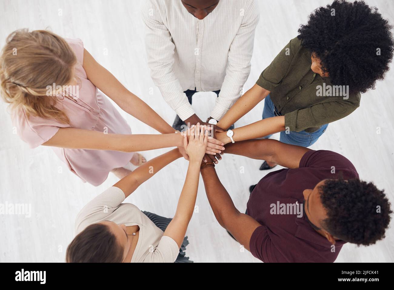 Group of five businesspeople stacking their hands together in an office ...