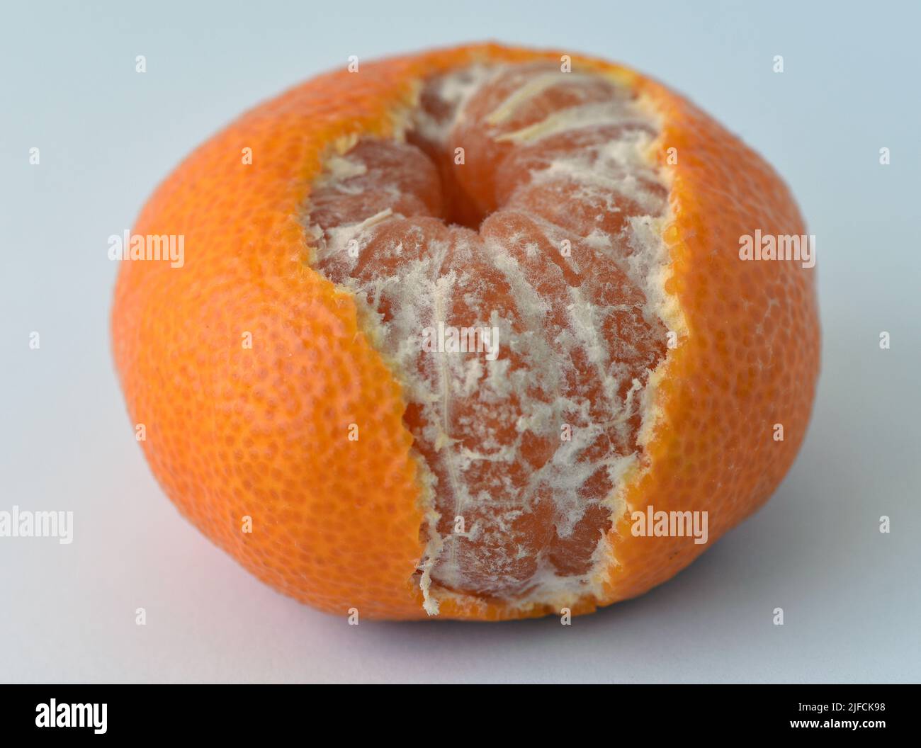 A view of the top of a partially peeled orange fruit with segments ...