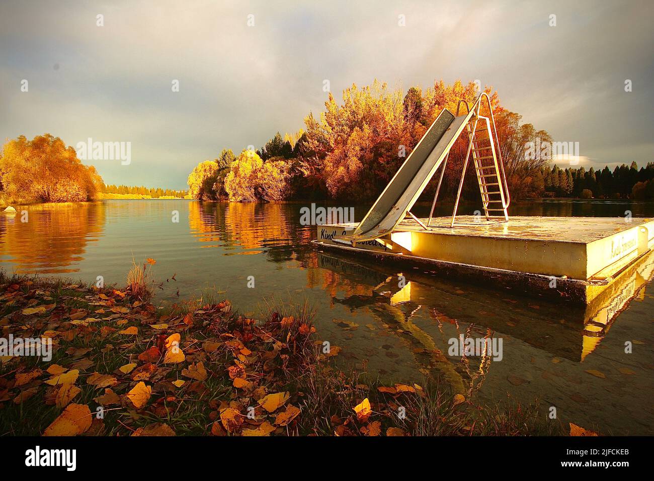 A water slide on floating dock on the lake surrounded by colorful trees ...