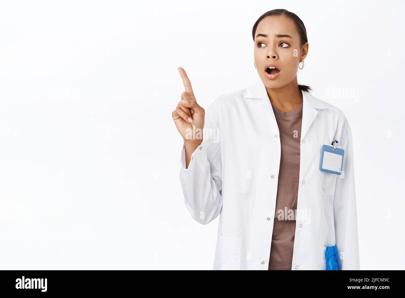 Portrait of female doctor pointing, looking at smth with concerned ...