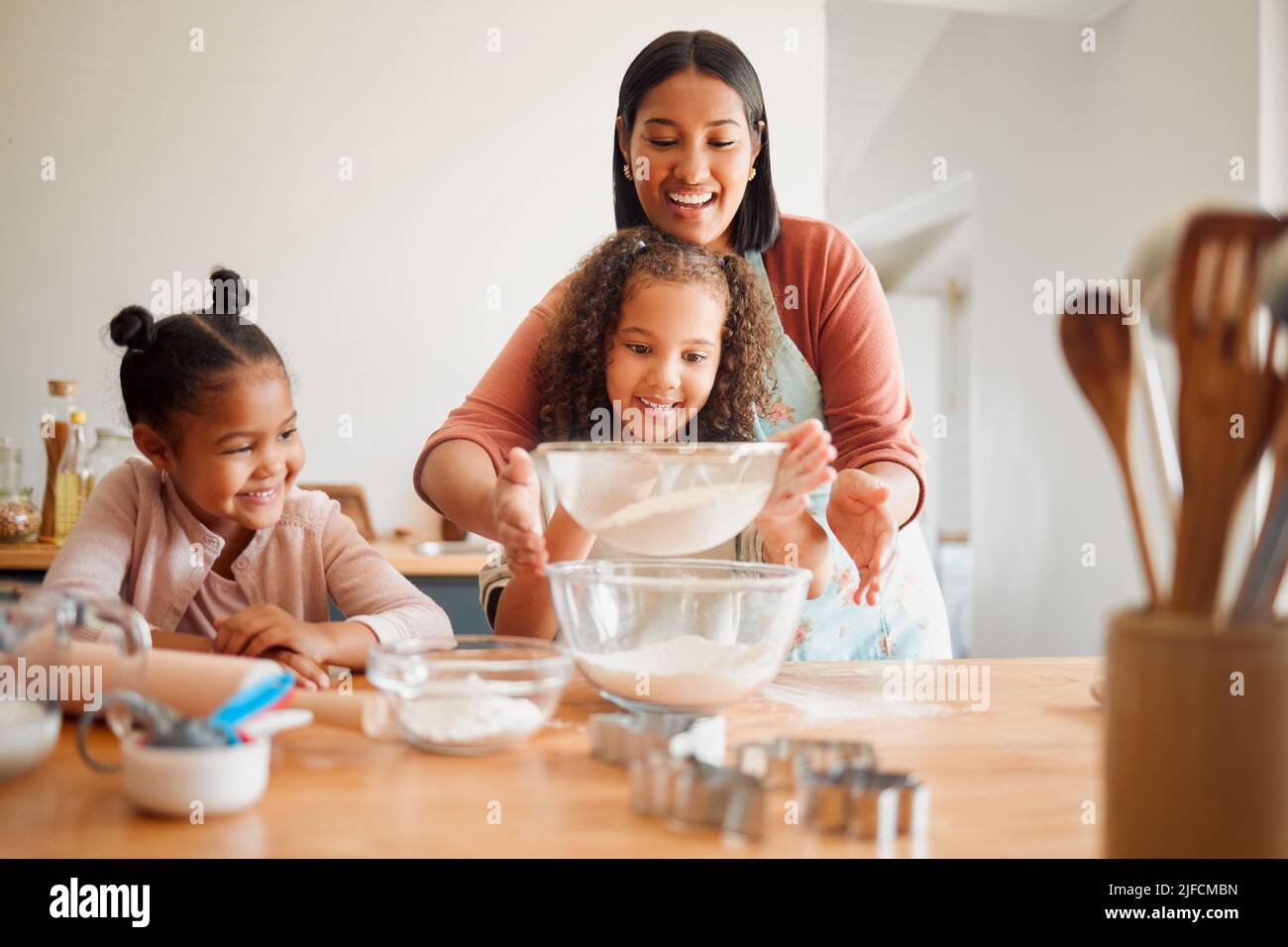 Females only, happy mixed race family of three cooking in a messy ...