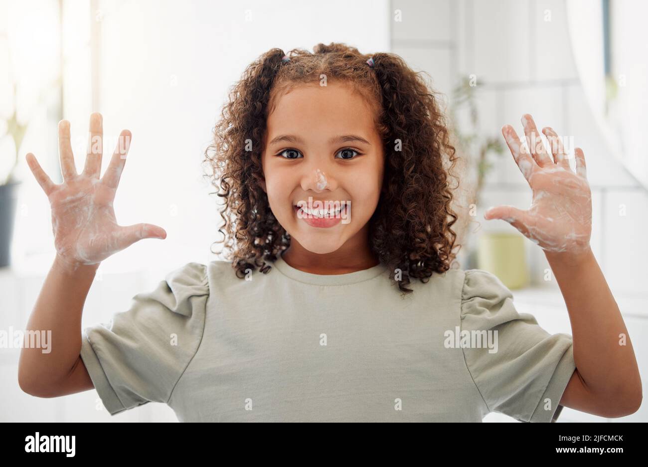 One mixed race adorable little girl washing her hands in a bathroom at ...