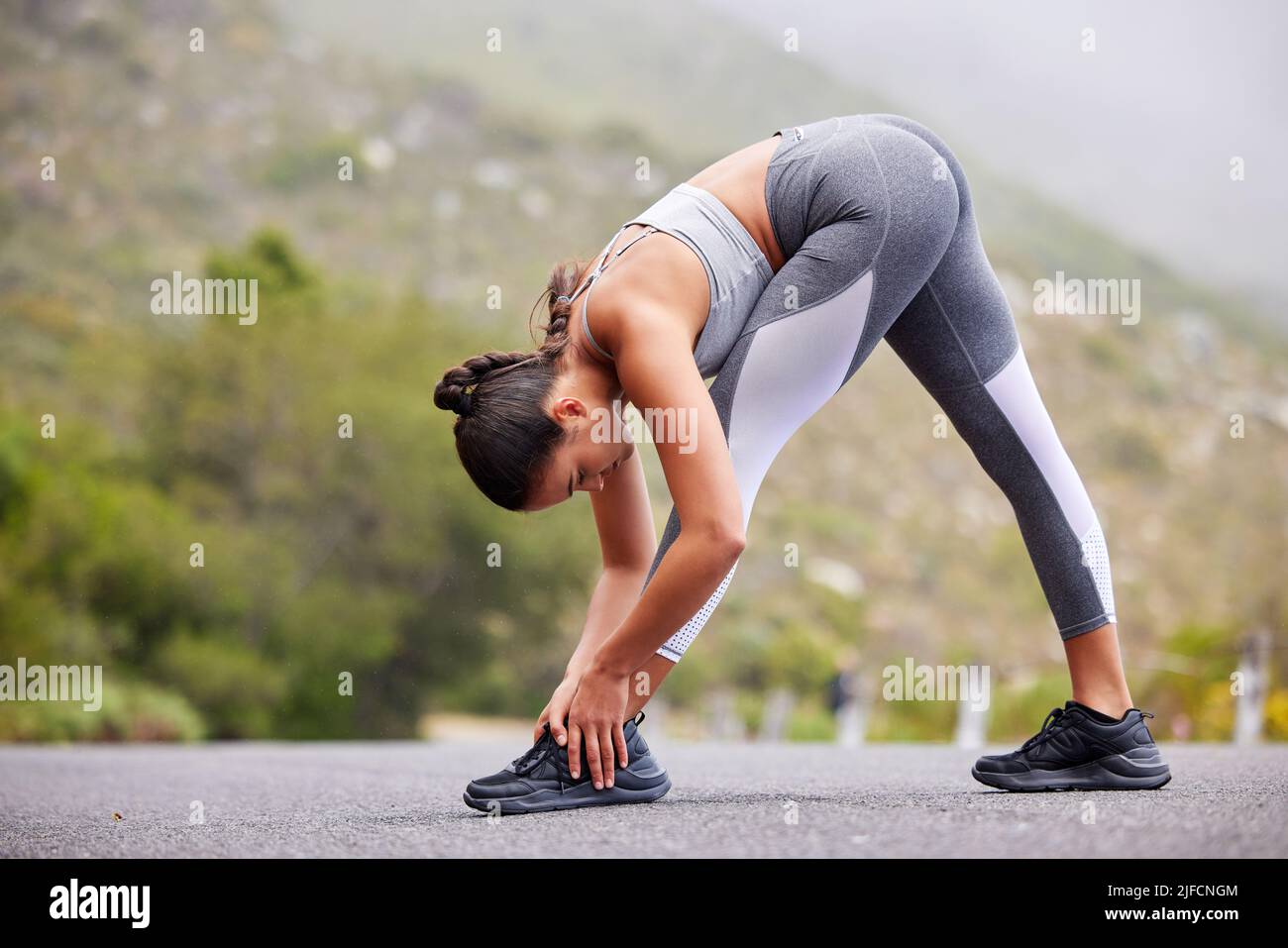 Active and fit young woman stretching her body while exercising ...