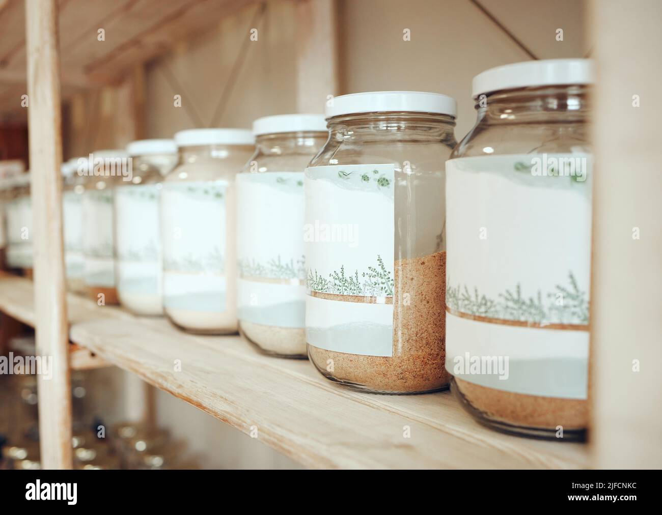 Glass jars of spices lined up in a row on a display shelf in a grocery ...