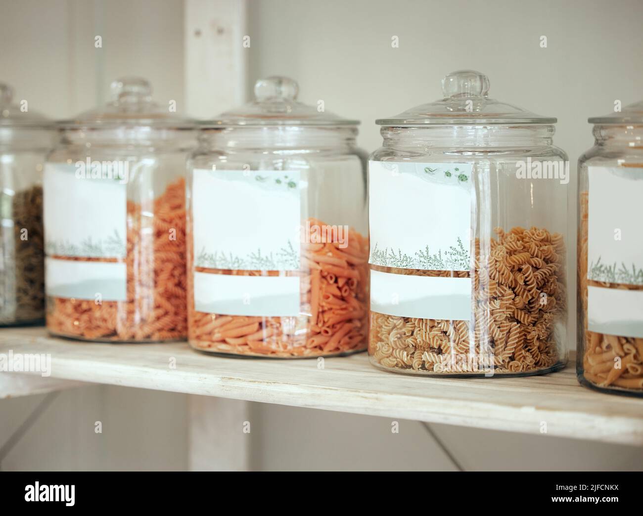 Glass jars of different types of pasta lined up in a row on a display ...