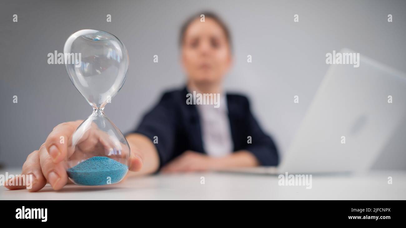 Business woman flipping an hourglass at her desk Stock Photo - Alamy