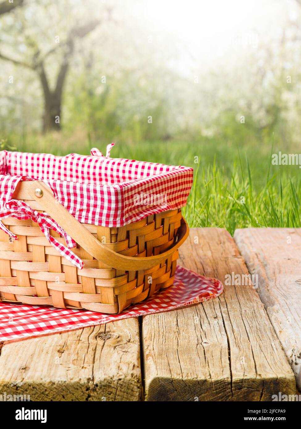 On a simple wooden table, a straw picnic basket against the backdrop of ...