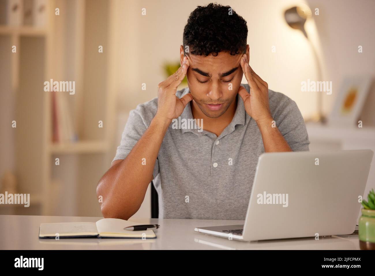 Young stressed man working alone on a laptop in an office at night. Guy ...