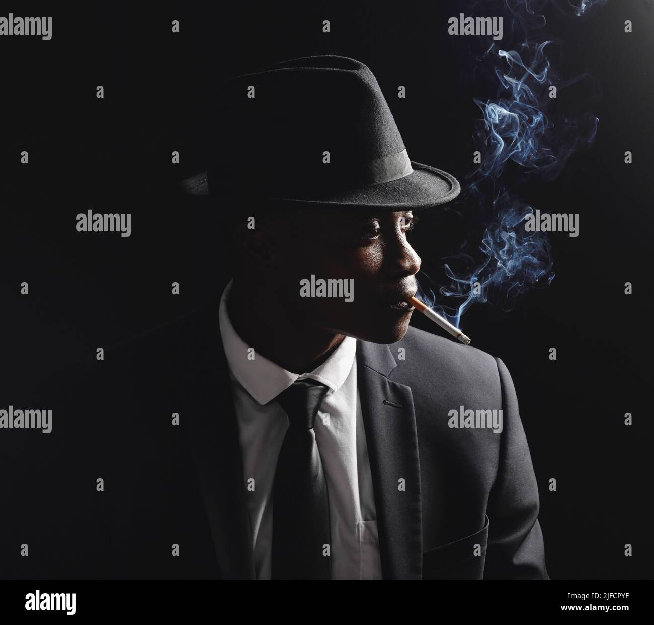 A young African american male looking serious while smoking a cigarette ...