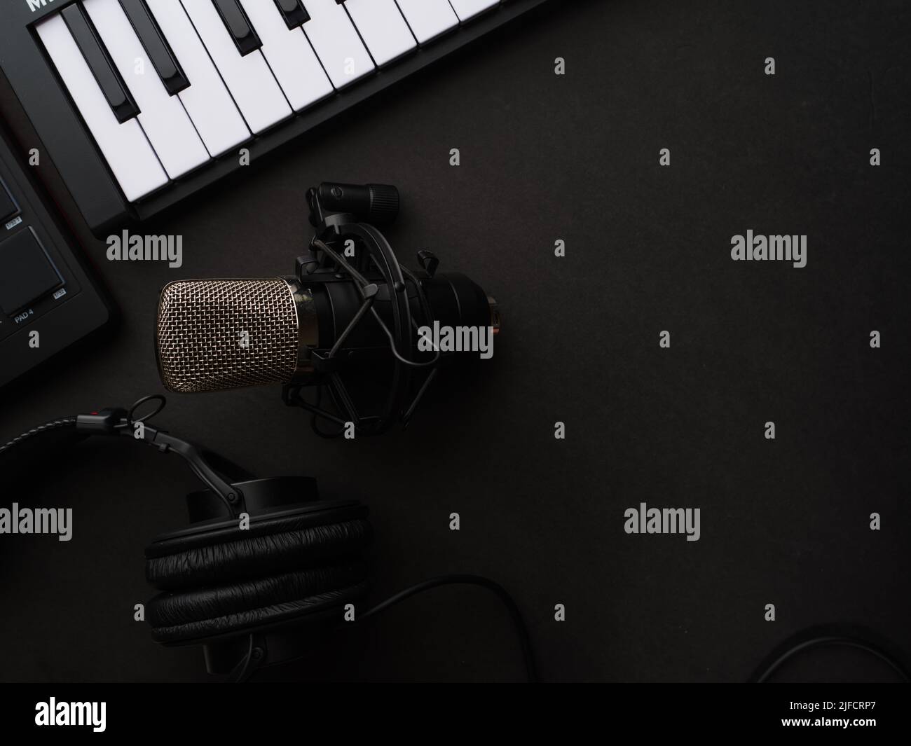 Professional studio equipment - midi keyboard, microphone and headphones on a dark gray ...