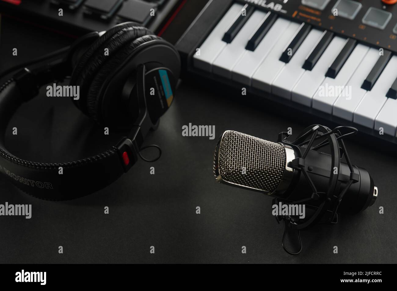 Midi keyboard, studio microphone and studio headphones on a dark gray ...