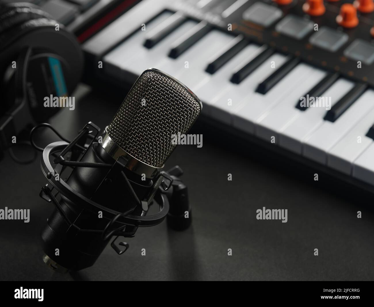 On a dark gray background, a professional studio microphone, headphones ...