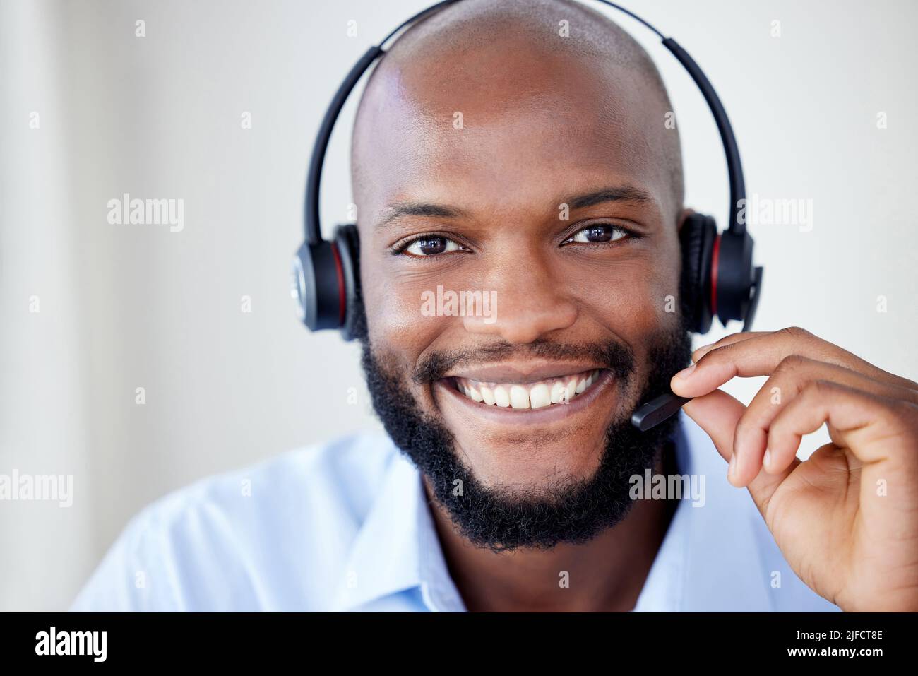 Black sales agents wearing a headset while working in a call centre ...