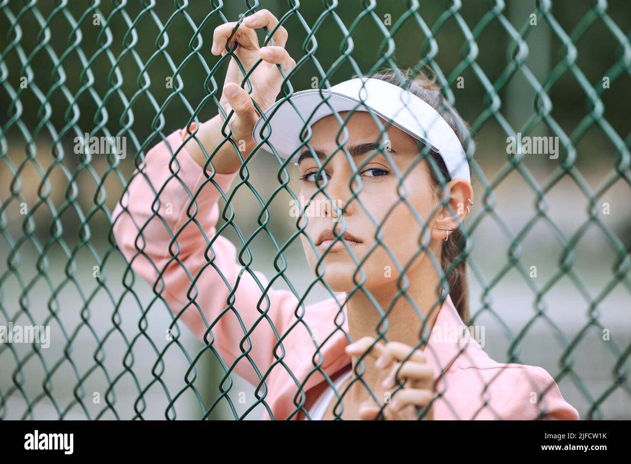 Close up of a female athlete leaning against a wire fence. Young ...
