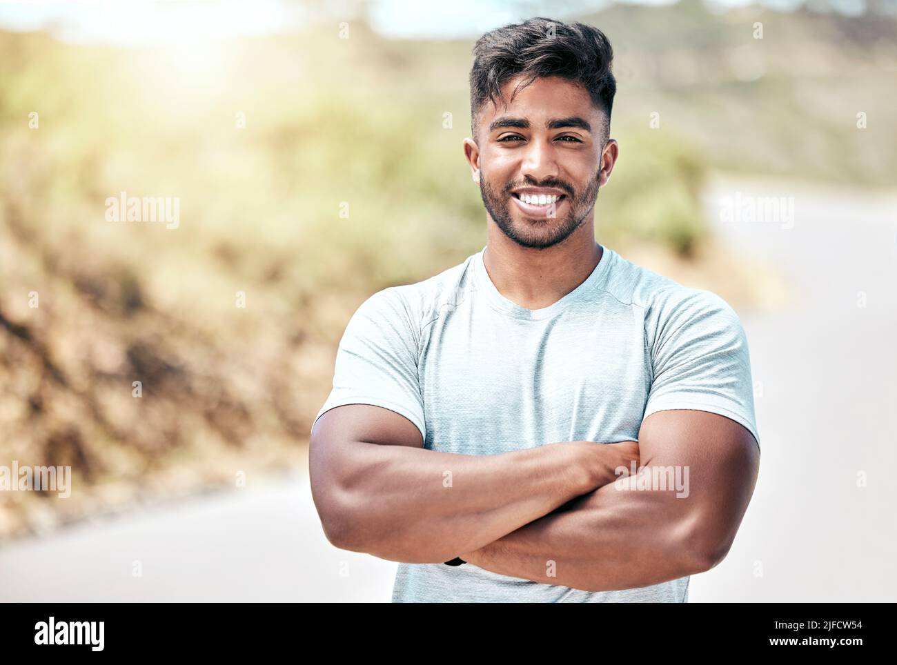 Portrait happy young mixed race man standing outside with his arms ...