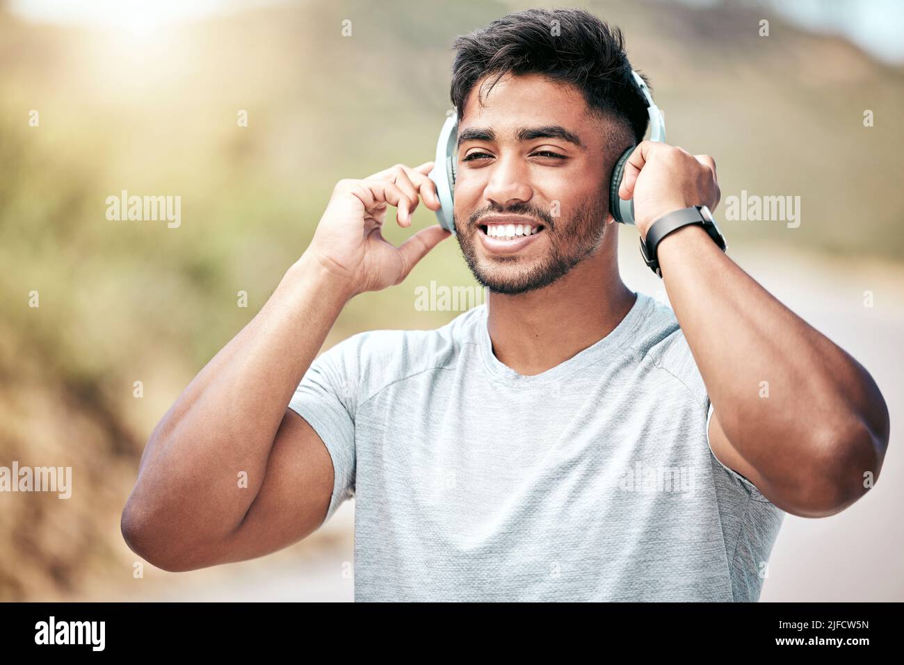 Fit young mixed race man listening to music on headphones while ...