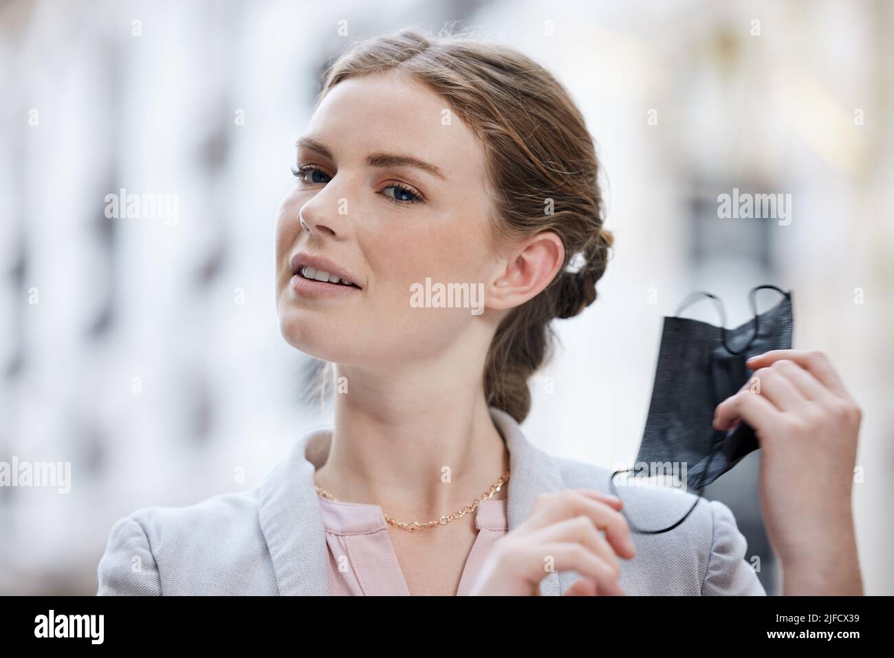 Woman removing her face mask while standing outside. Woman removing her ...