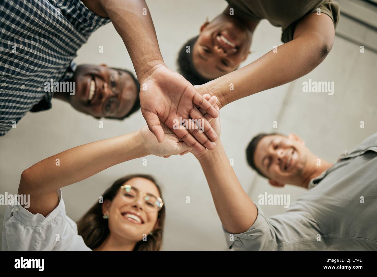 Cheerful group of colleagues putting hands together in the office ...