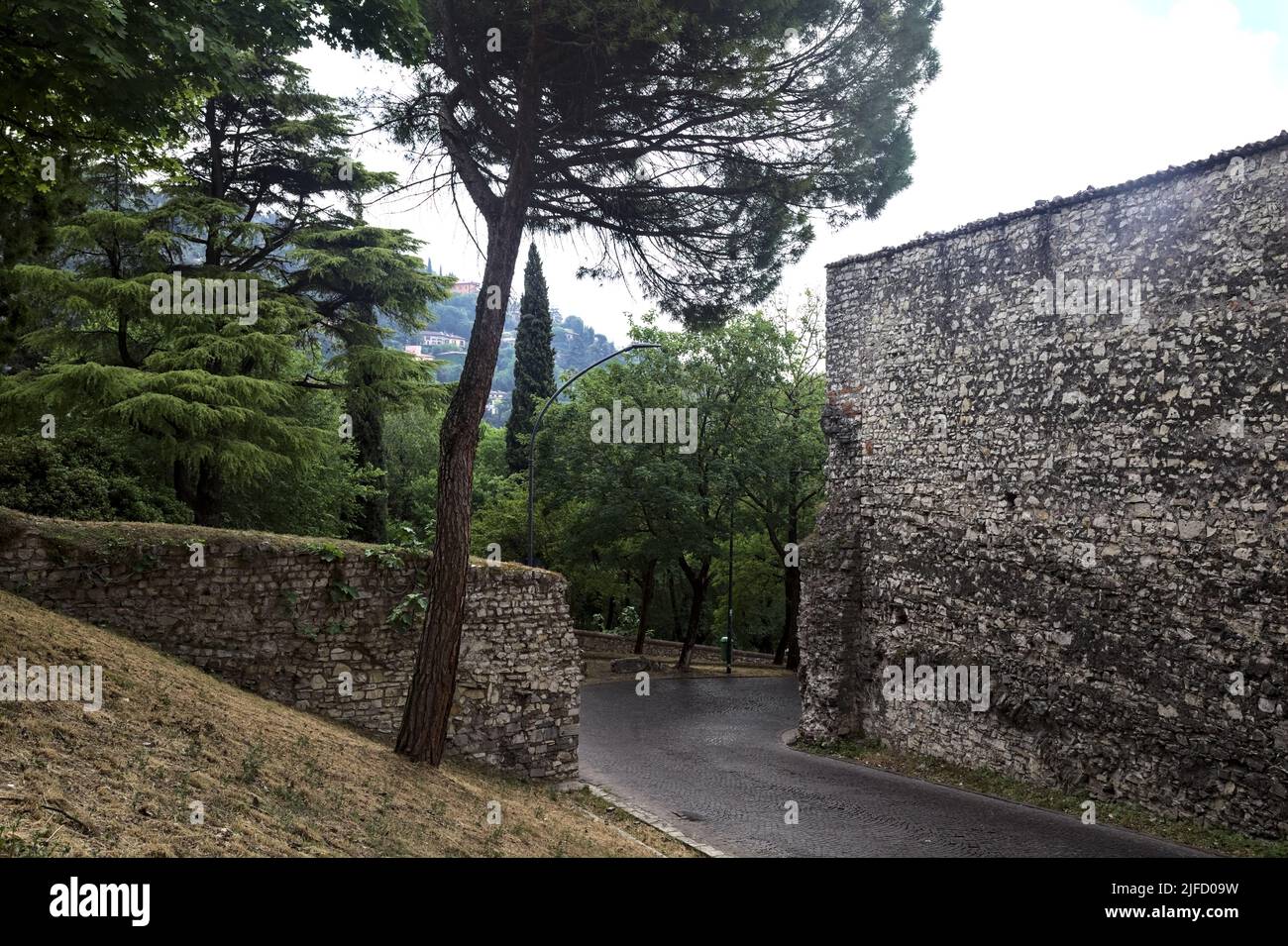 Paved road next to a stone boundary wall in the middle of a park Stock ...