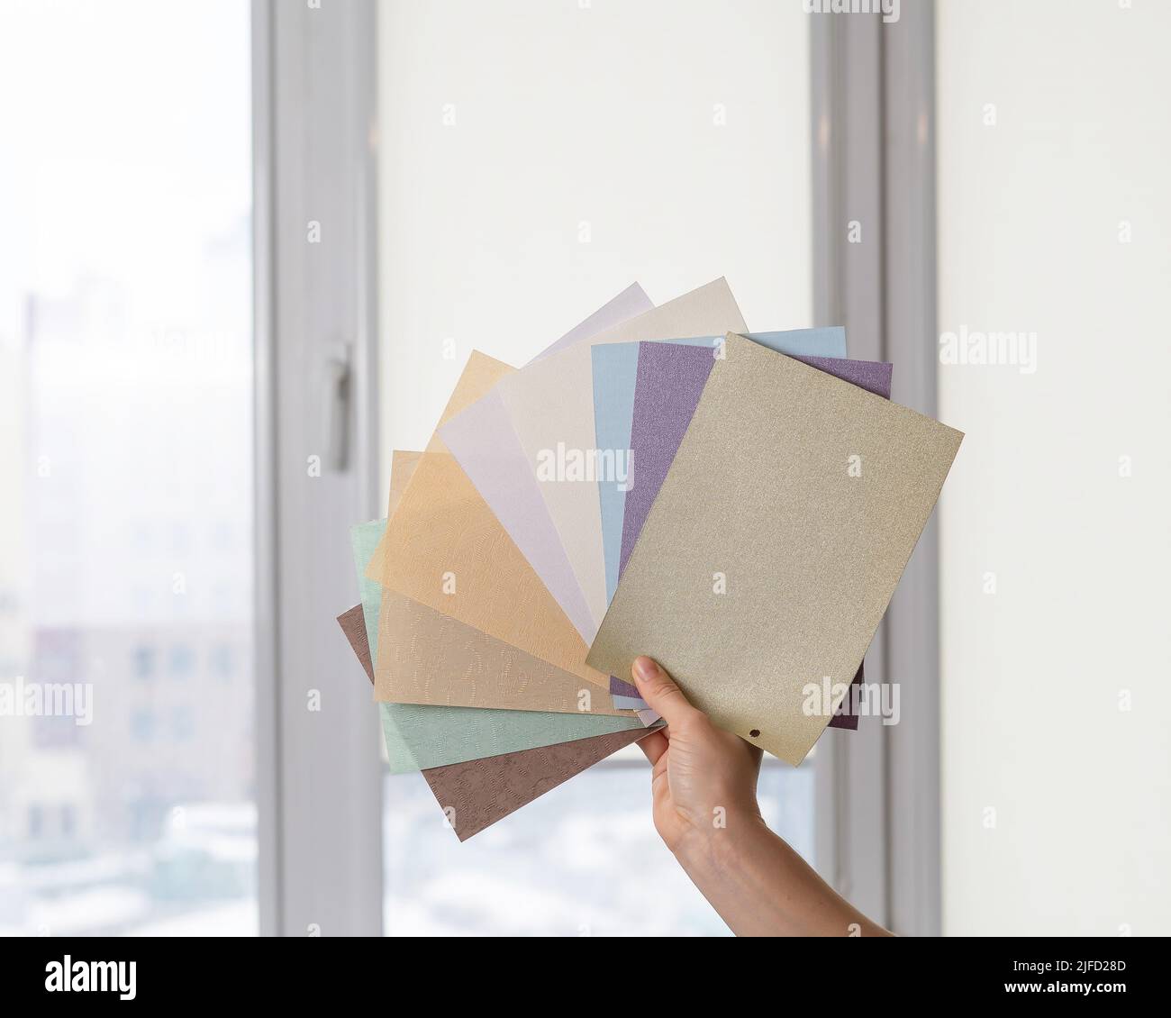 Woman holding fabric samples of roller blinds against window background ...