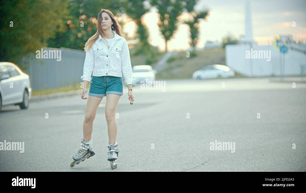 A shy teenage girl in rollerblades skating on the road Stock Photo - Alamy