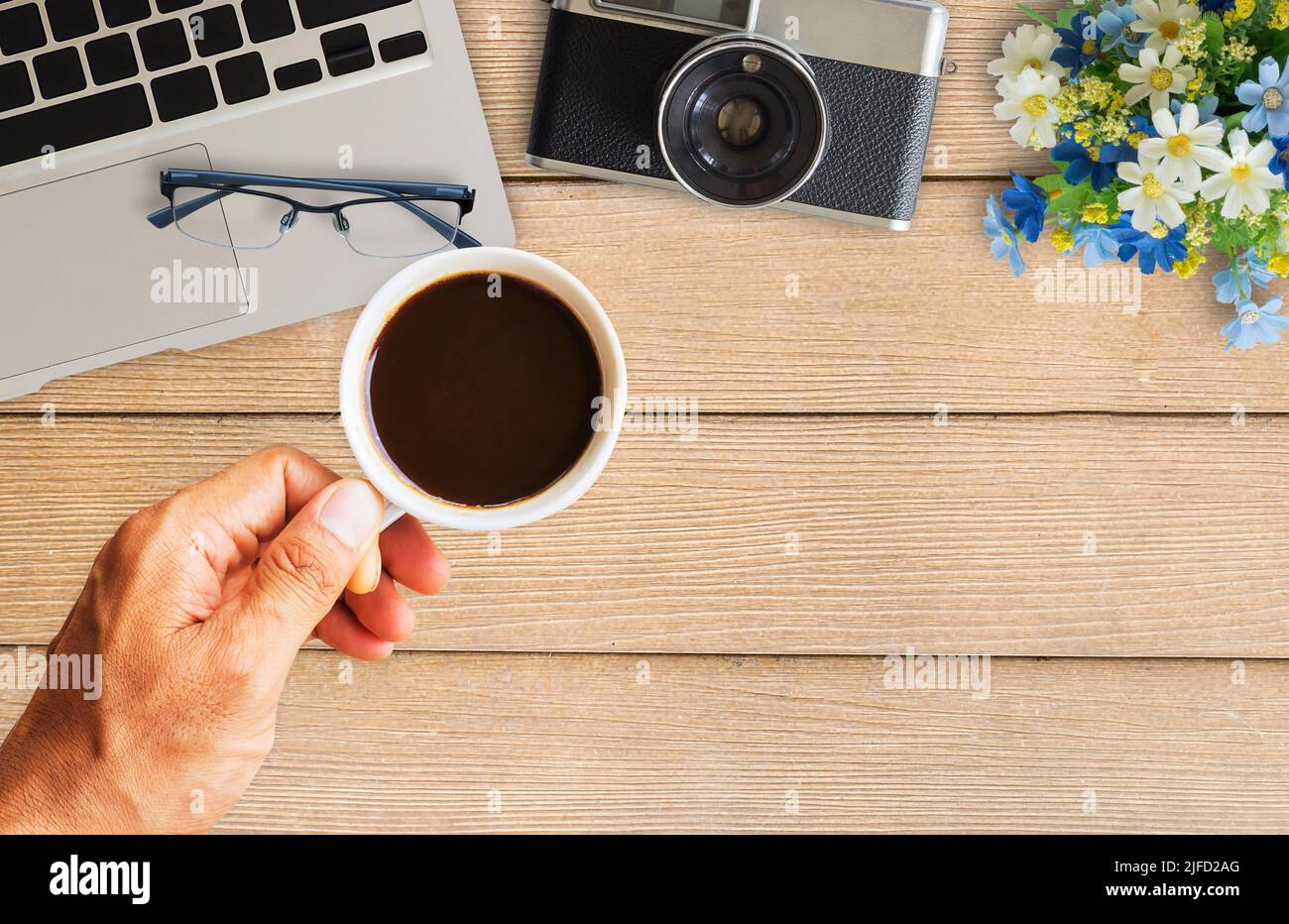 Business man holding a cup of coffee and office desk table with laptop ...