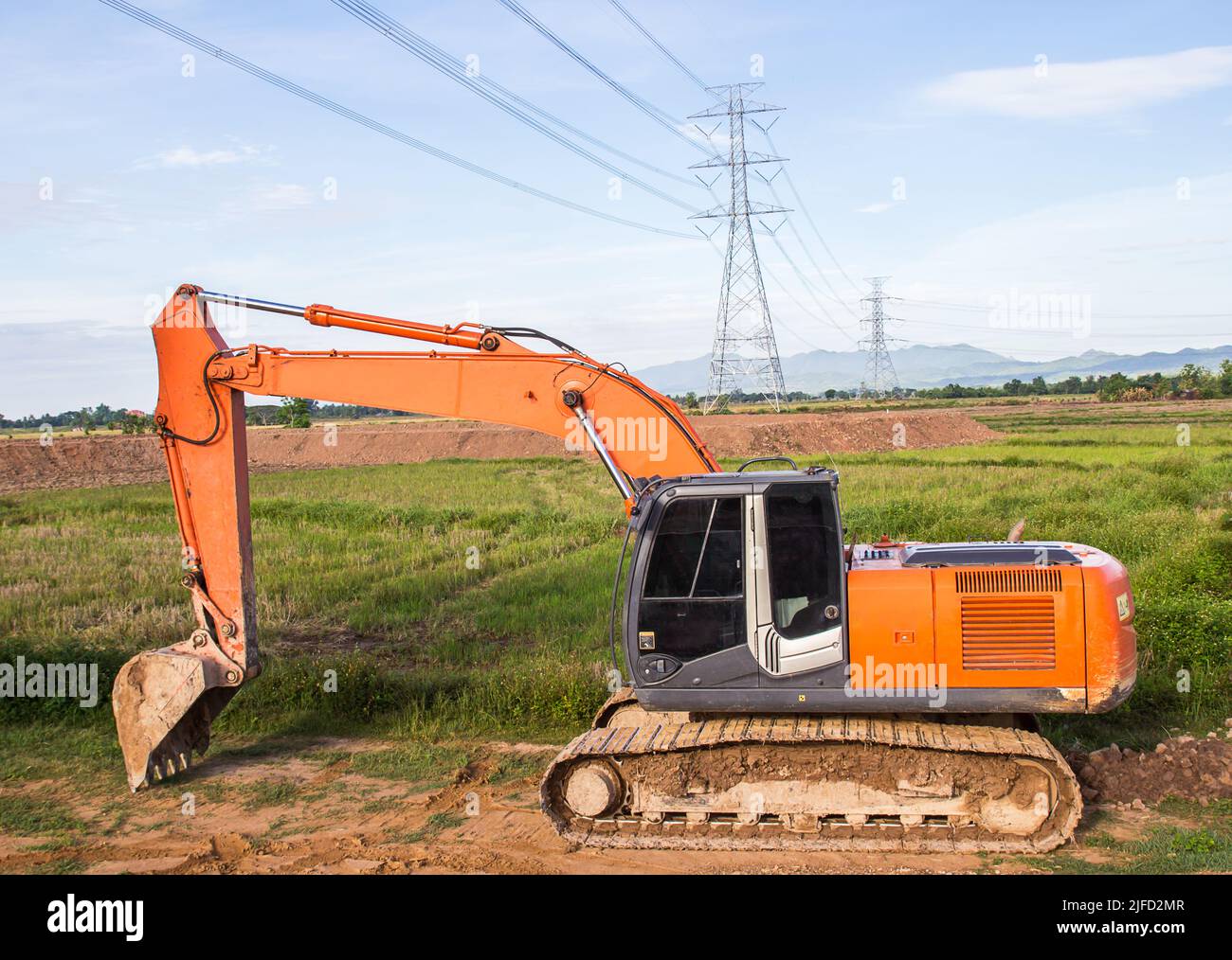 Excavator orange machinery, in the construction site. near high voltage ...