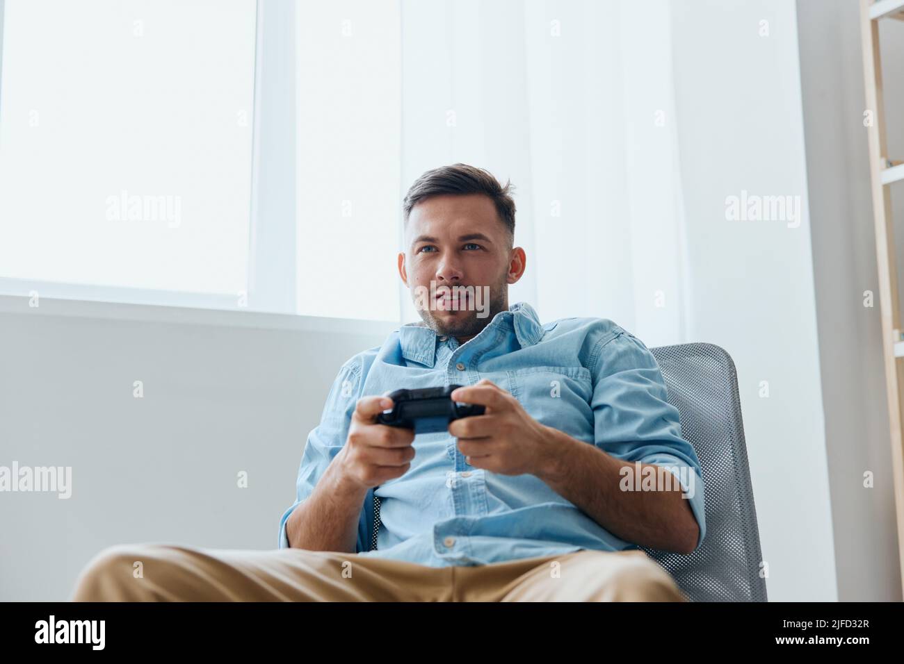 Overjoyed focused young tanned enthusiastically play with joystick ...