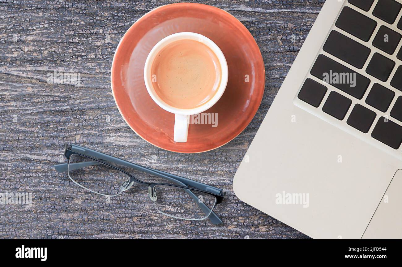 Work office desk with laptop computer and hot coffee cup. Top view ...