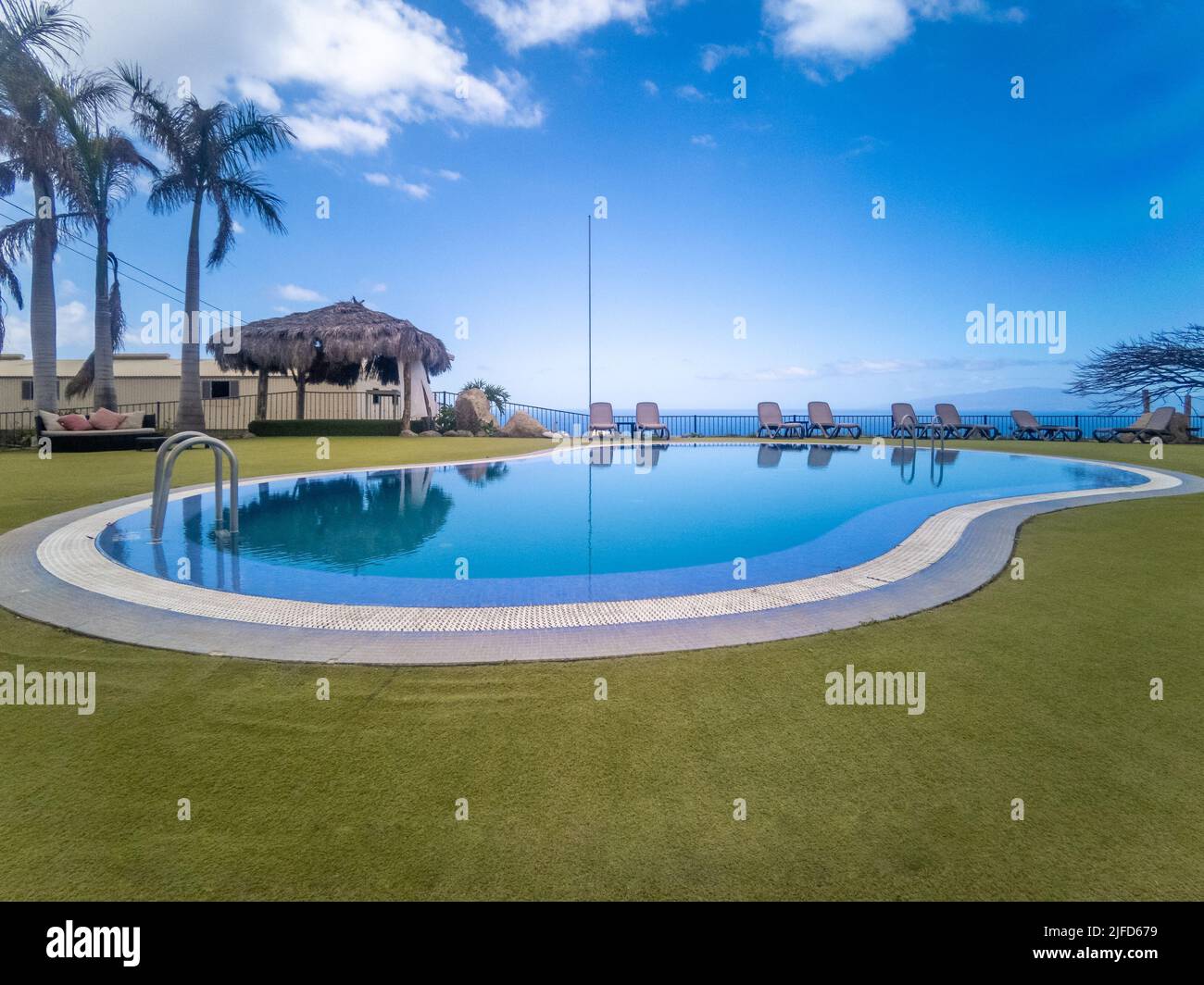 A view of a swimming pool reflecting beach chairs and an alcove Stock ...