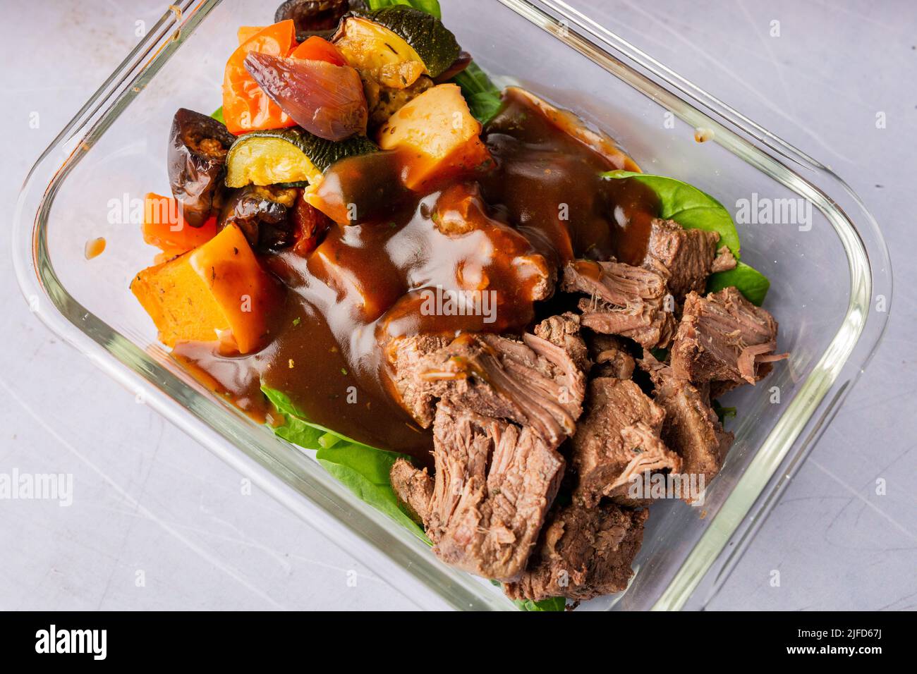 A top view of beef prepared with vegetables and a sauce in a ...