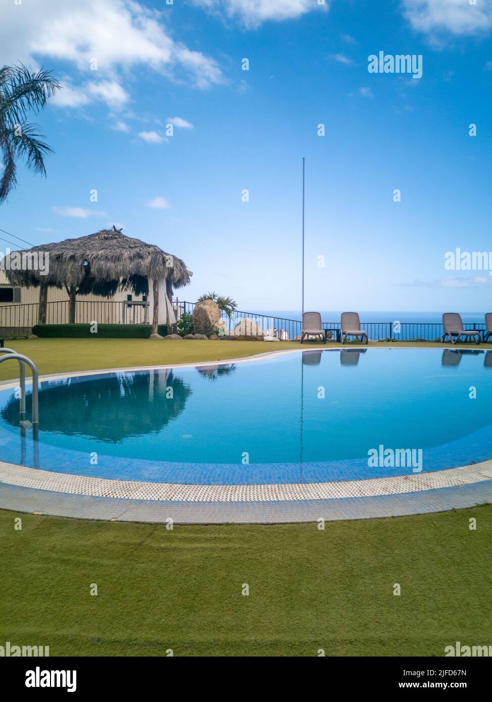 A vertical shot of a swimming pool surrounded by beach chairs and an ...
