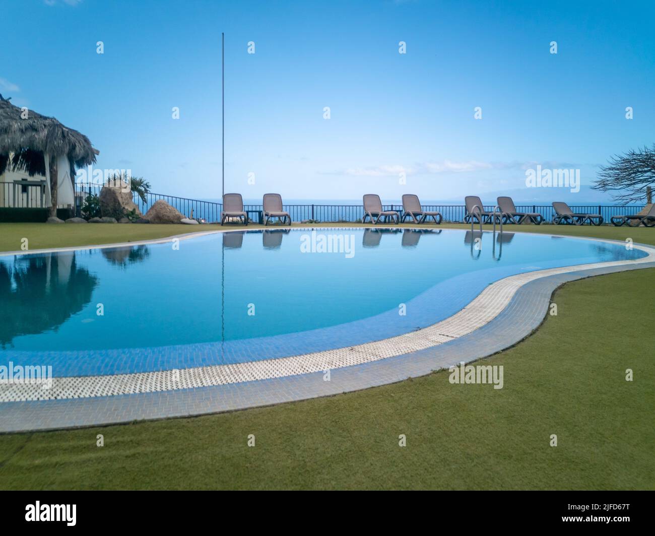 A view of a swimming pool reflecting beach chairs and an alcove Stock ...